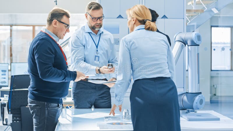 Diverse Team of Industrial Robotics Engineers Gathered Around Table ...