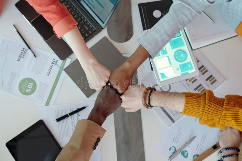 Diverse Team Members Fist Bumping Over Desk in Office Stock Photo ...