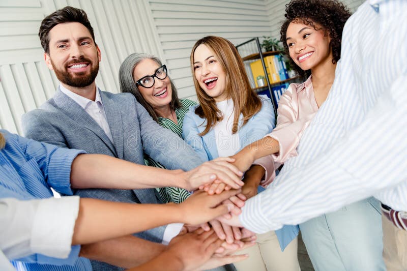 Diverse Work Colleagues Joining Hands Symbolizing Teamwork and Collaboration in an Office ...