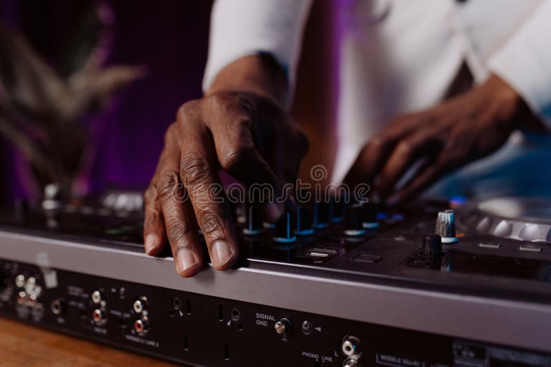 DJ Mixing Console with Hand Adjusting Controls in a Dimly Lit Setup ...