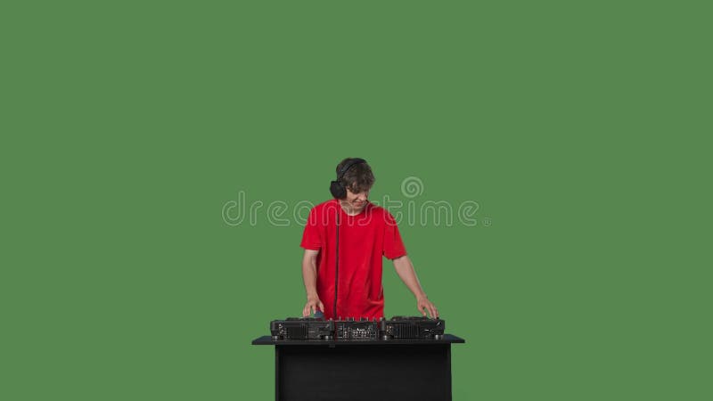 DJ Mixing Music on a Turntable in a Studio on a Green Screen Background ...