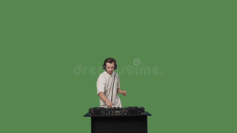 DJ Mixing Music on a Turntable in a Studio on a Green Screen Background ...