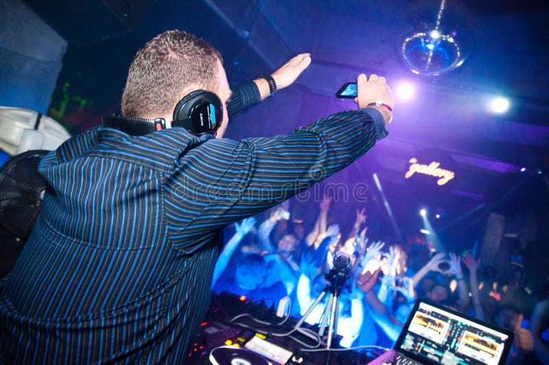 DJ Hands Up at Night Club Party Under Blue Light with Crowd of People ...