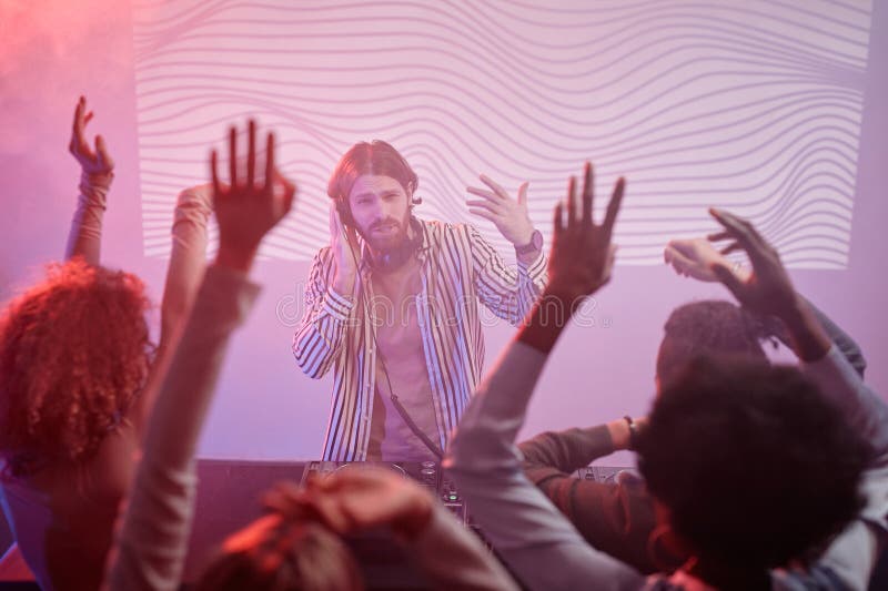 DJ by Turntable in Neon Lights Cheering for Dancing Crowd Stock Photo ...