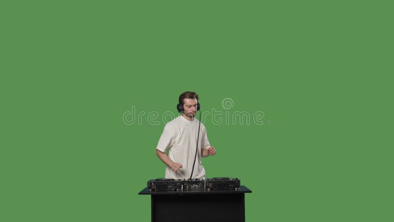 DJ Mixing Music on a Turntable in a Studio on a Green Screen Background ...