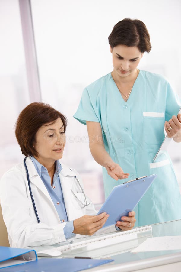 Doctor and Assistant Discussing Work Stock Photo - Image of holding ...