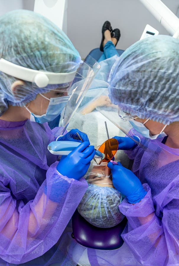 Doctor with an Assistant in a Protective Suit and Goggles Using UV Lamp ...