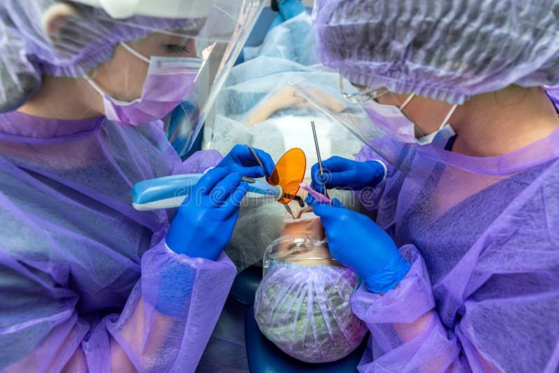 Doctor with an Assistant in a Protective Suit and Goggles Using UV Lamp ...
