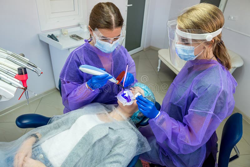Doctor with an Assistant in a Protective Suit and Goggles Using UV Lamp ...