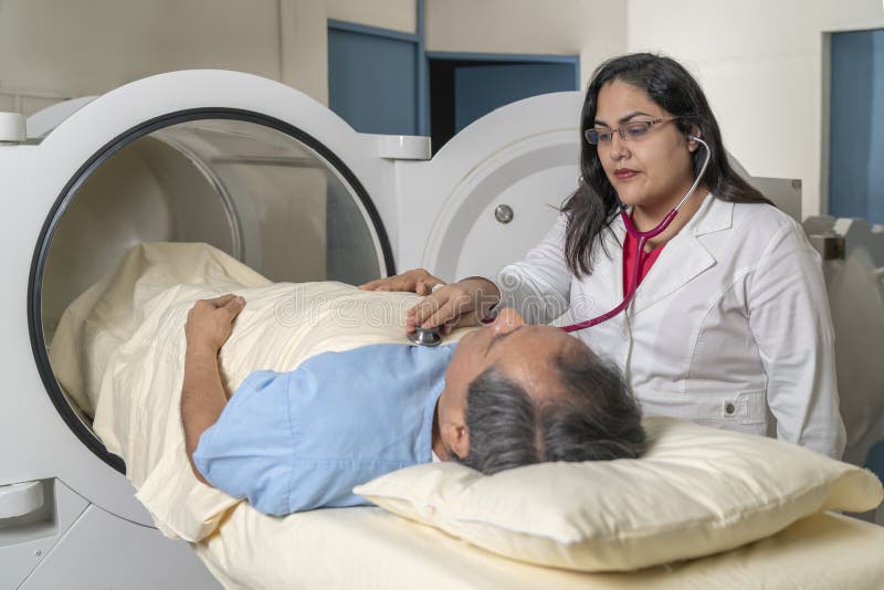 Doctor Auscultating a Patient on a Stretcher in Front of a Hyperbaric ...