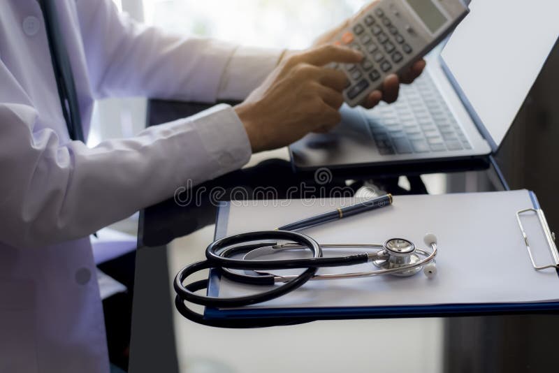Male Doctor or Physician Using Calculator and Work on Laptop Computer ...