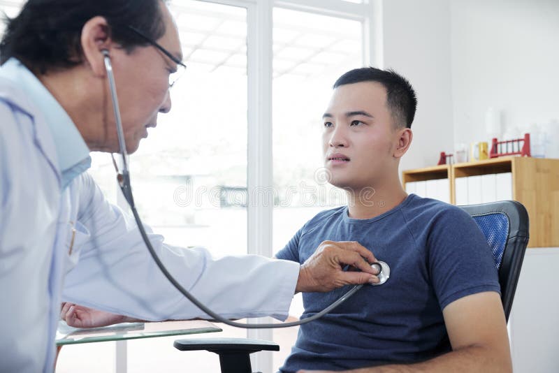 Doctor Checking Heartbeat of Young Man Stock Photo - Image of ...
