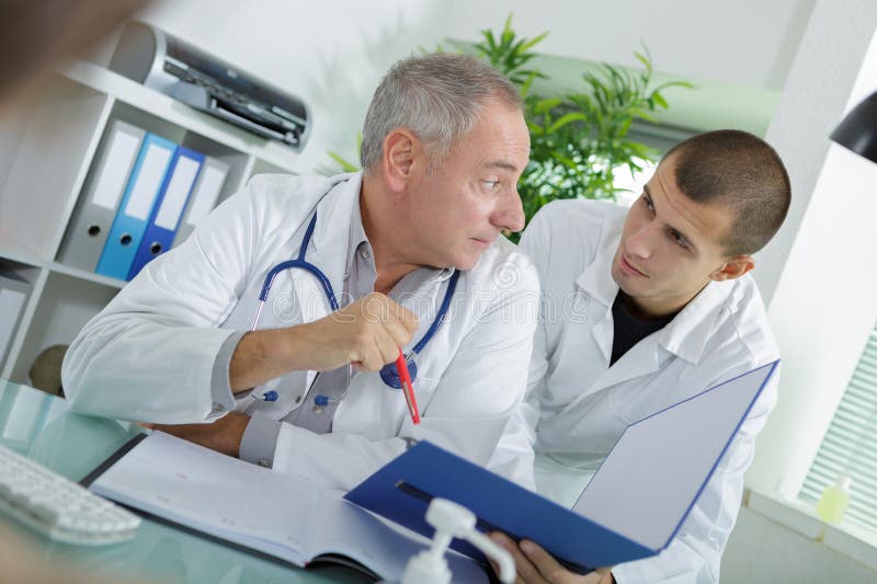 Doctor Checking Medical Records with Assistant Stock Image - Image of ...