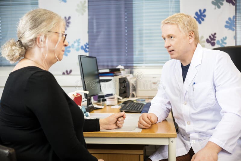 Doctor Communicating with Senior Patient at Desk Stock Image - Image of ...
