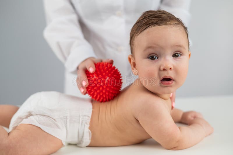 A Doctor Gives a Child a Back Massage Using a Ball. Stock Image - Image ...