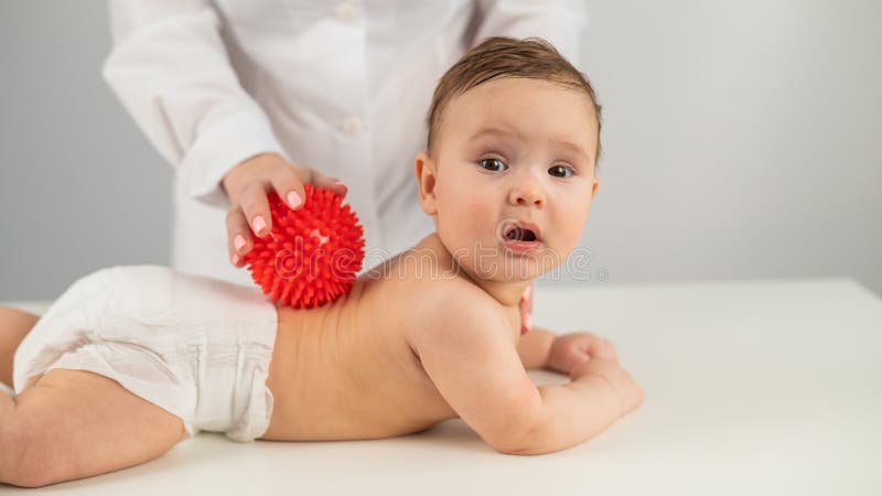 A Doctor Gives a Child a Back Massage Using a Ball. Stock Image - Image ...