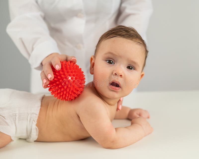 A Doctor Gives a Child a Back Massage Using a Ball. Stock Photo - Image ...