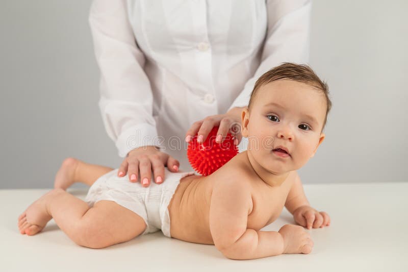 A Doctor Gives a Child a Back Massage Using a Ball. Stock Photo - Image ...