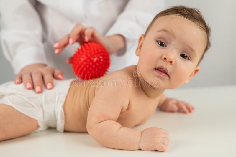 A Doctor Gives a Child a Back Massage Using a Ball. Stock Photo - Image ...
