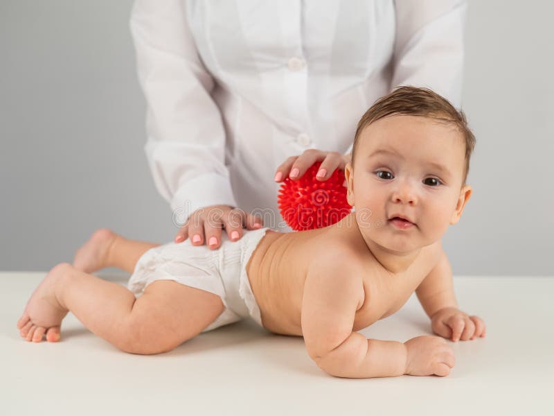 A Doctor Gives a Child a Back Massage Using a Ball. Stock Image - Image ...