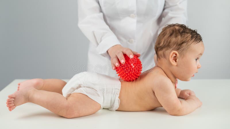 A Doctor Gives a Child a Back Massage Using a Ball. Stock Image - Image ...