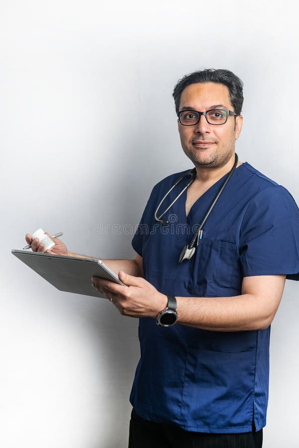 Doctor in Glasses with a Stethoscope Writes Data into a Tablet Computer ...