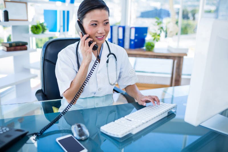 Doctor Having Phone Call and Using Her Computer Stock Image - Image of ...