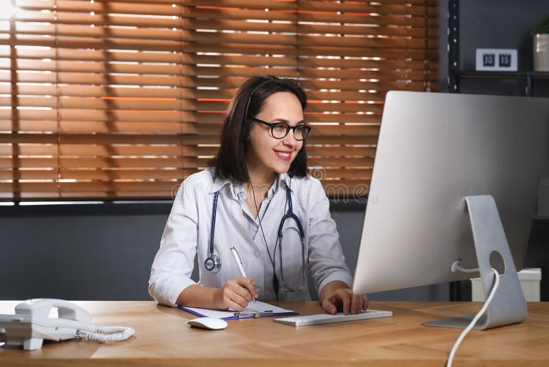 Doctor with Headset and Computer Consulting Patient Online in Office ...