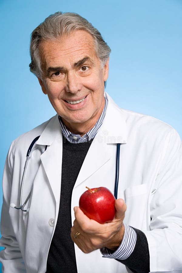 Doctor holding an apple stock photo. Image of camera - 62560770