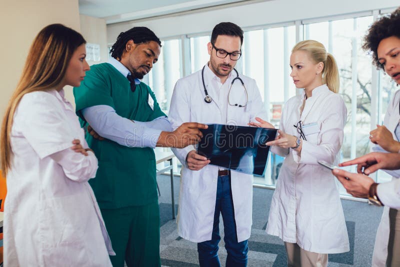 Doctor Holding Up an X-ray with Fellow Doctors Stock Photo - Image of ...