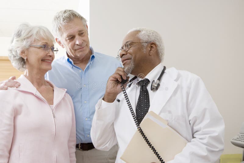 Doctor Looking At Patients While Using Landline Phone Stock Photo ...