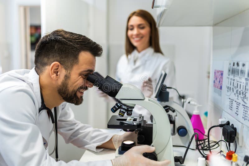Doctor Looking Thru Microscope while Doing Research in His Lab Stock ...