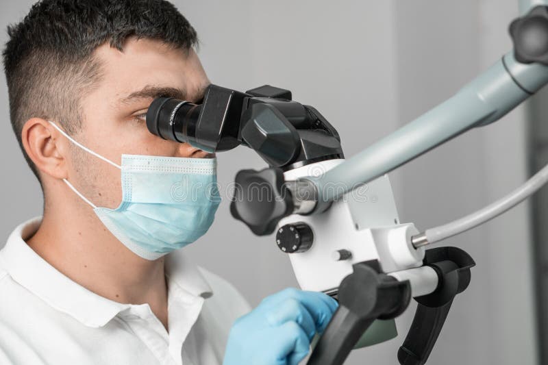 A Doctor Looks through a Microscope in Close-up. Dental Microscope at ...