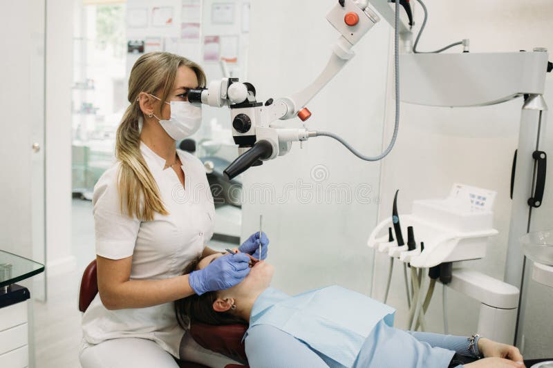 Female Dentist Using Dental Microscope Treating Patient Teeth at Dental ...