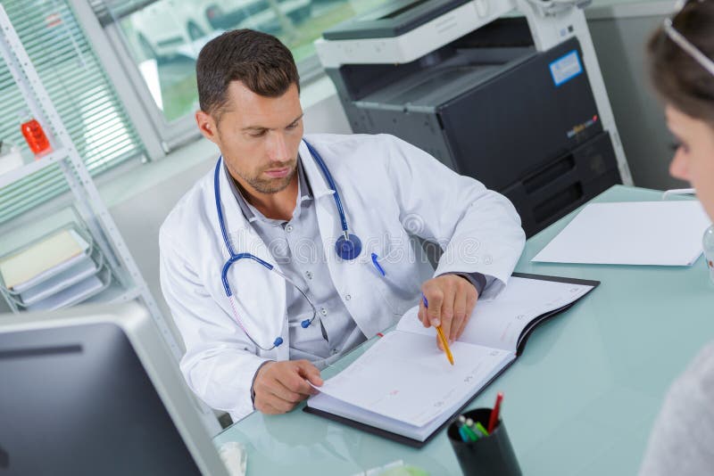 Doctor with Patient Looking through Diary Stock Image - Image of ...