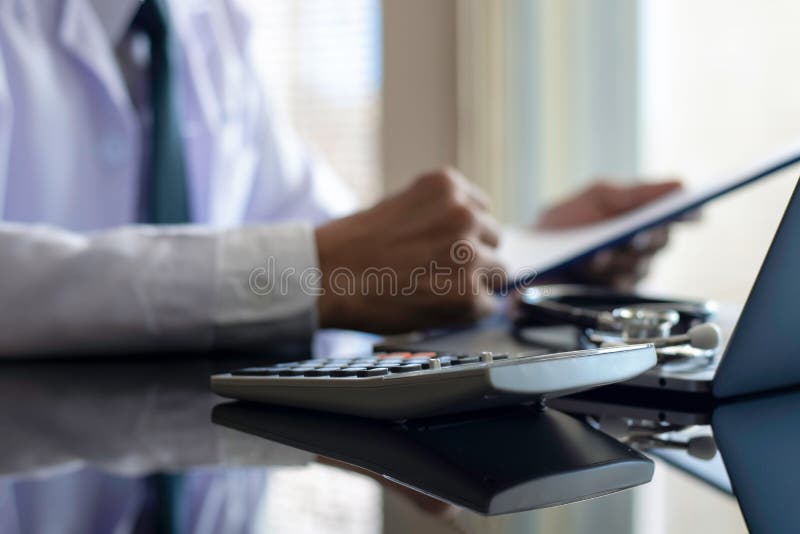 Doctor or Practitioner Using Calculator and Work on Laptop Computer ...