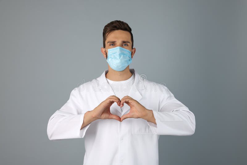 Doctor in Protective Mask Making Heart with Hands on Grey Background ...