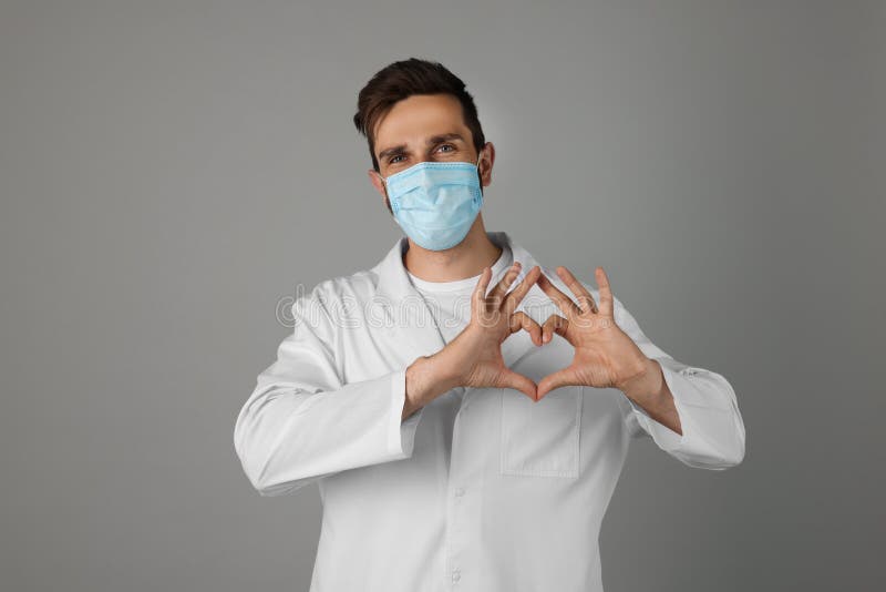 Doctor in Protective Mask Making Heart with Hands on Grey Background ...