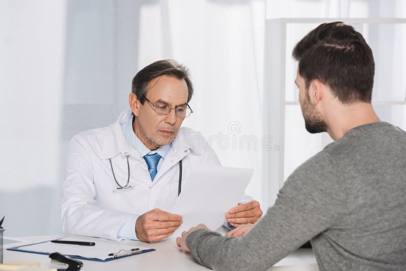 Doctor Reading Male Patient Stock Photo - Image of mature, book: 119791432
