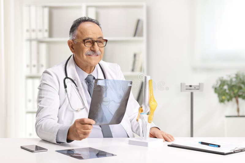 Doctor Sitting Behind a Desk and Checking an X-ray Image Stock Photo ...