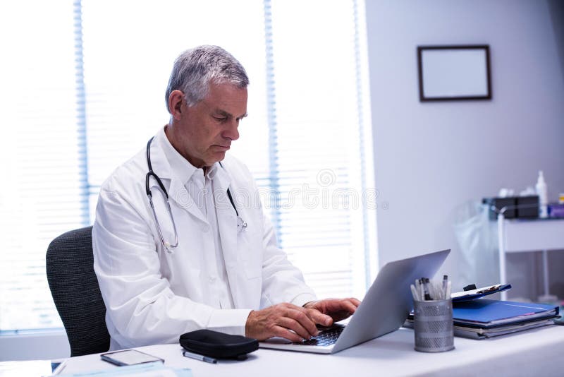 Doctor Sitting at Table and Using Laptop Stock Photo - Image of file ...
