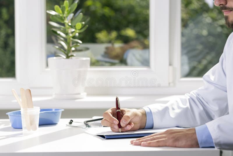 Doctor Sitting by the Table and Writing a Document Stock Image - Image ...