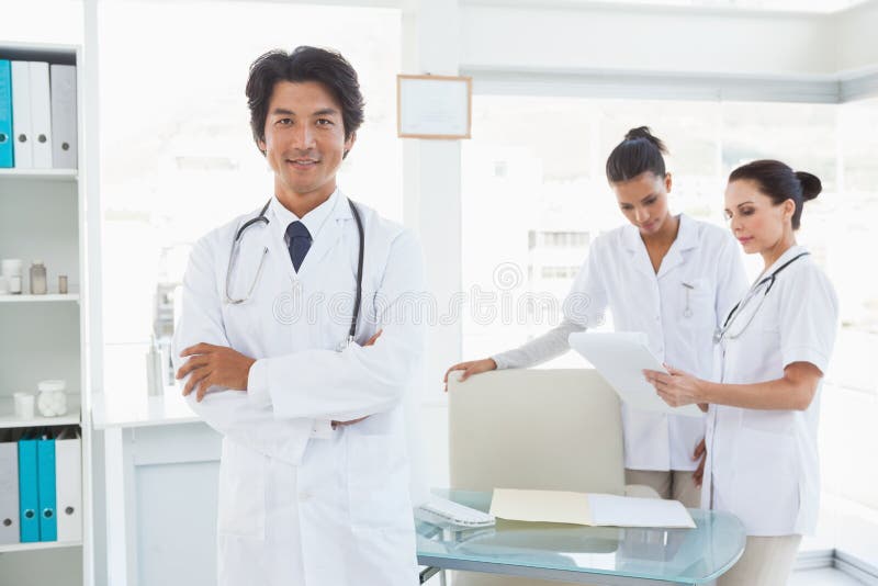 Doctor Smiling in Front of Work Colleagues Stock Image - Image of male ...