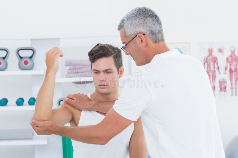 Doctor Stretching a Young Man Arm Stock Image - Image of physical ...