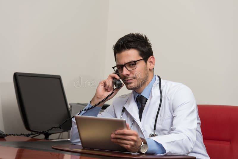 Doctor Talking on Telephone and Using Computer Stock Image - Image of ...