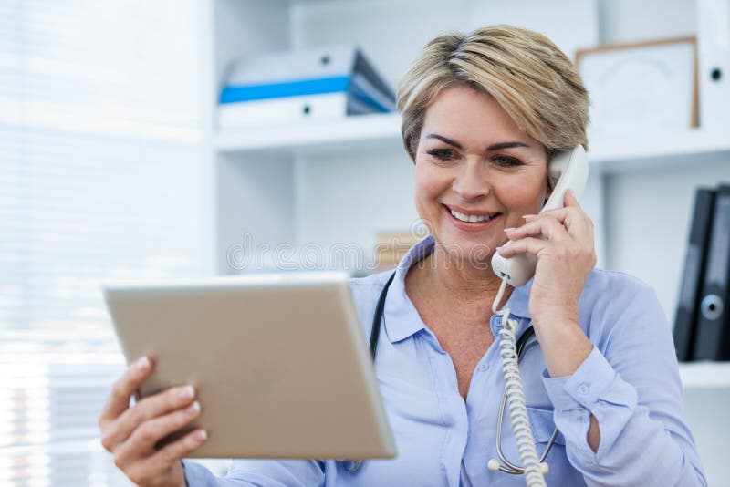 Doctor Talking on Telephone while Using Digital Tablet Stock Image ...