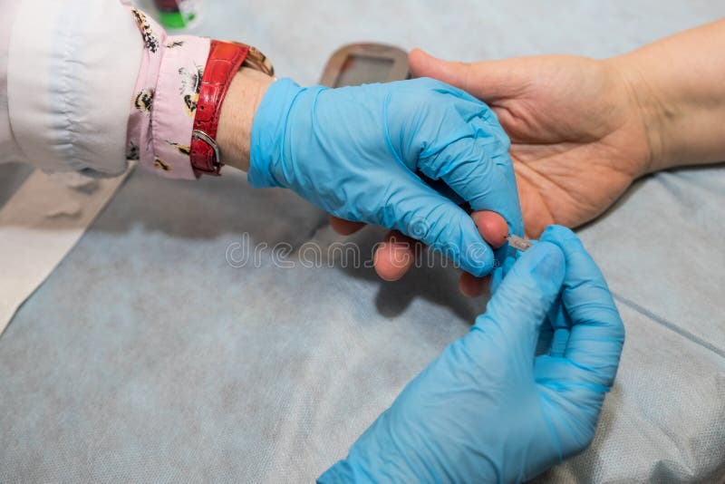 Doctor Testing a Patients Glucose Level after Pricking His Finger To ...
