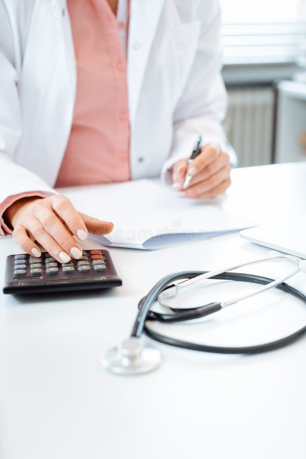Doctor Using Calculator Writing Bills and Doing Bookkeeping Stock Image ...