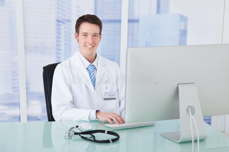 Doctor Using Computer at Desk in Clinic Stock Image - Image of handsome ...