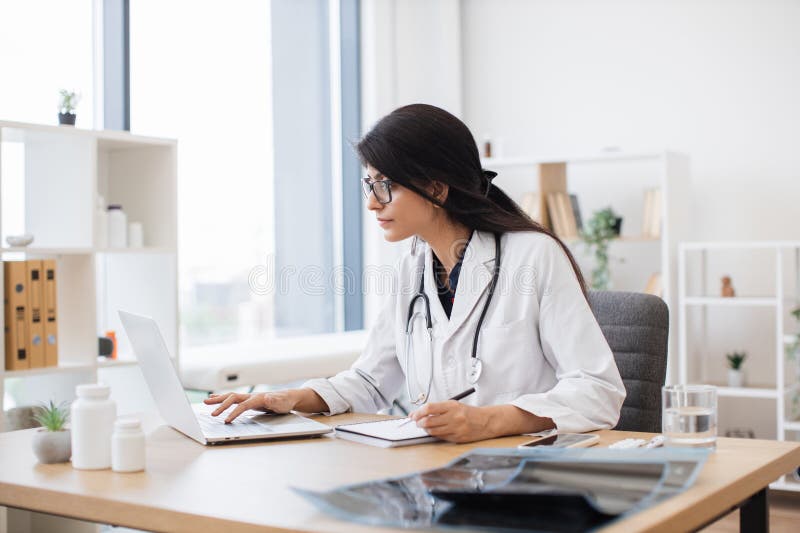 Doctor Using Computer while Sitting at Desk in Health Center Stock ...